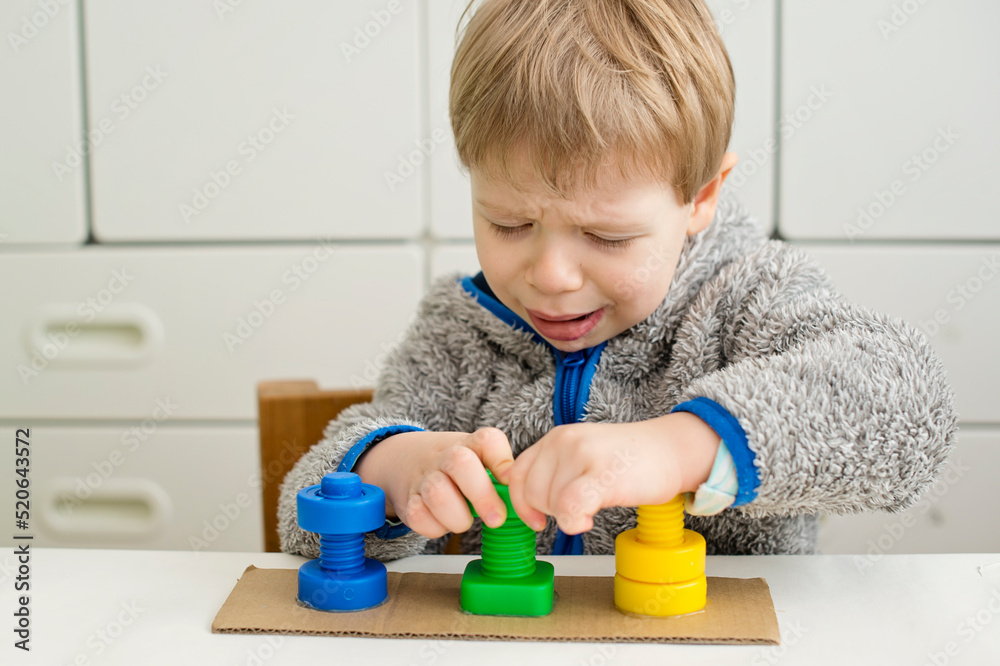 Shapes, colors and fine motor skills. toddler turns the nut on the bolt ...