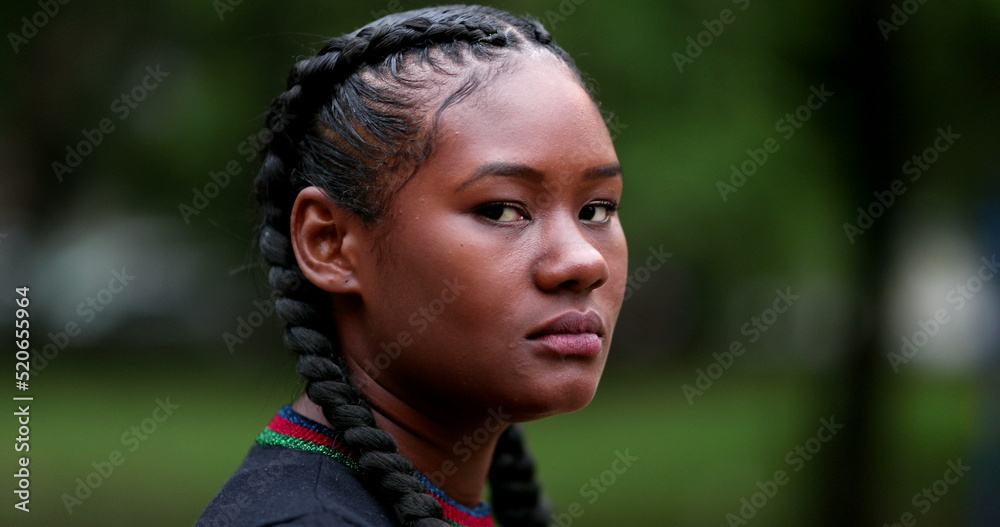 Serious young black woman looking at camera outside. Dramatic African ...