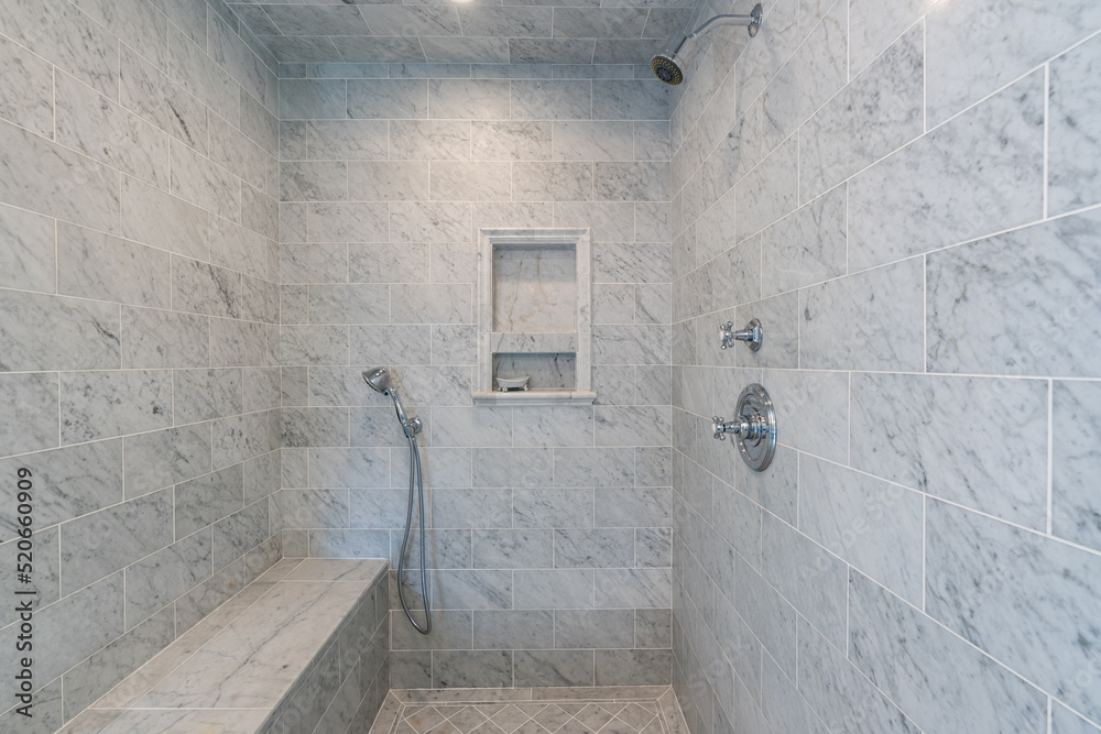 Luxury walk in shower with gray and white marble walls, bench, and ...