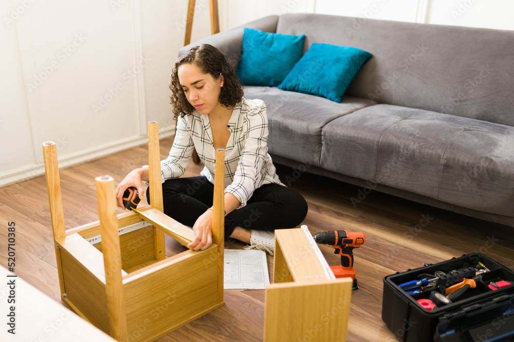 Caucasian woman measuring a table while building self assembly ...