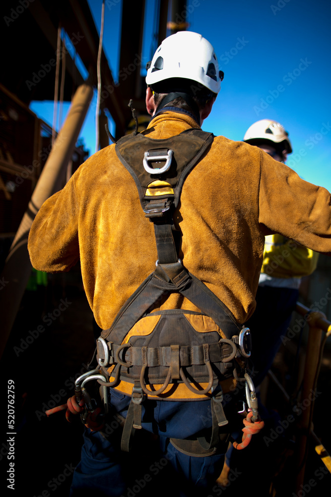 Back side of international rope access male welder wearing a safety ...