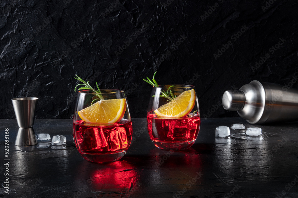 Campari cocktail with fresh oranges, a shaker, and a jigger on a black ...