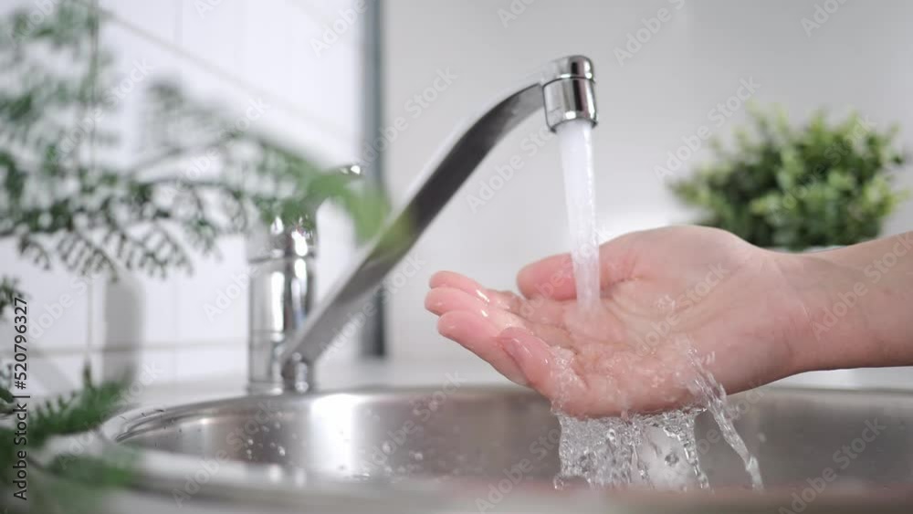 A stream of clean water drink flows into human hands. Wash hands and ...