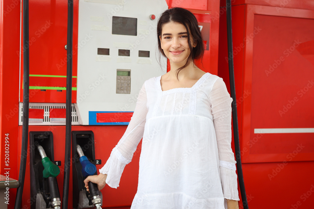 Portrait of happy smiling customer woman holding fuel petrol pump ...
