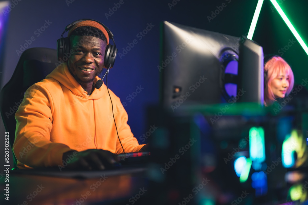 Young black man in orange hoodie wearing headset competing in online ...