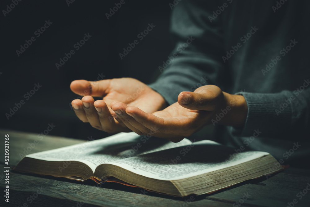 Hands open palm up in prayer on a Holy Bible in church concept for ...