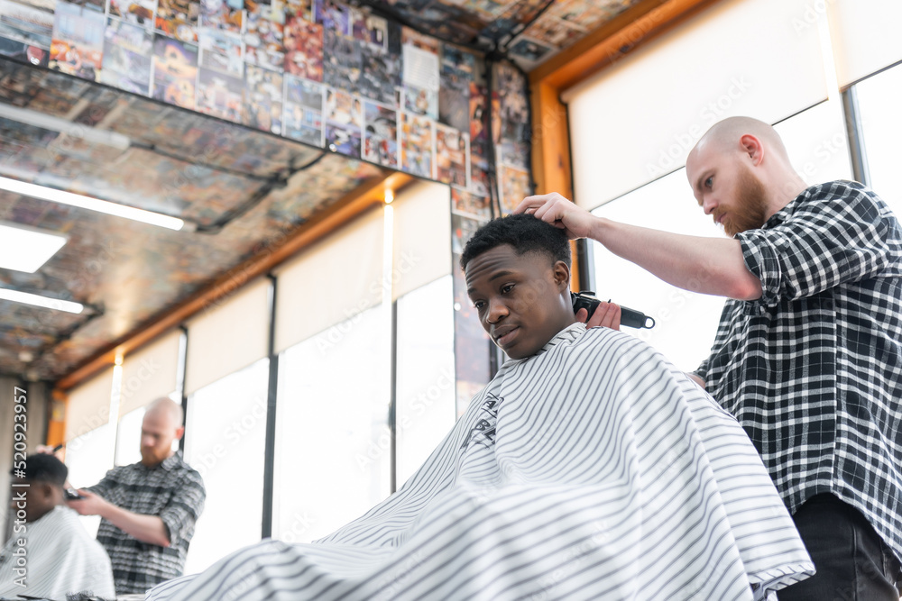 Foto de Man at the barbershop. Handsome black man getting a haircut in ...