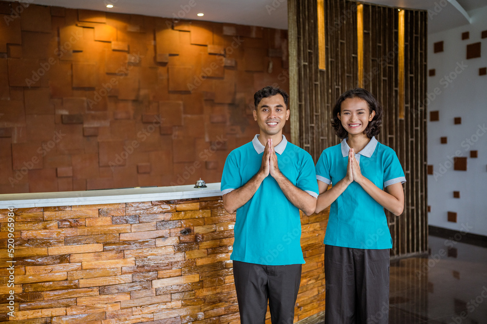 two receptionists wearing turquoise uniforms smiling with welcome hands ...