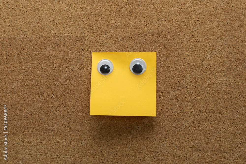 googly eyes on clean orange sticky note on cork board concept using ...