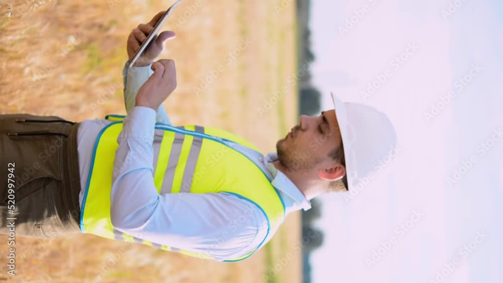 Silhouette of an electrical engineer in hard hat at sunset with tablet ...