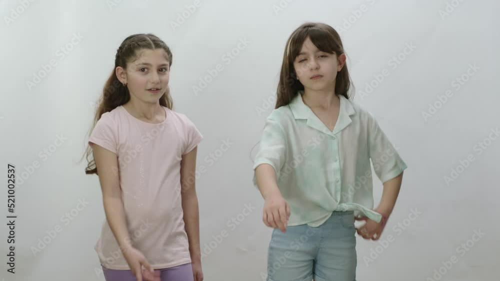 Two girls standing next to each other on a white background.Little ...
