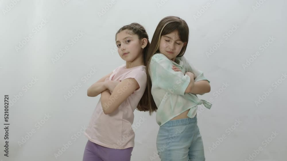 Two girls lean against each other in isolation. Energetic little girls ...