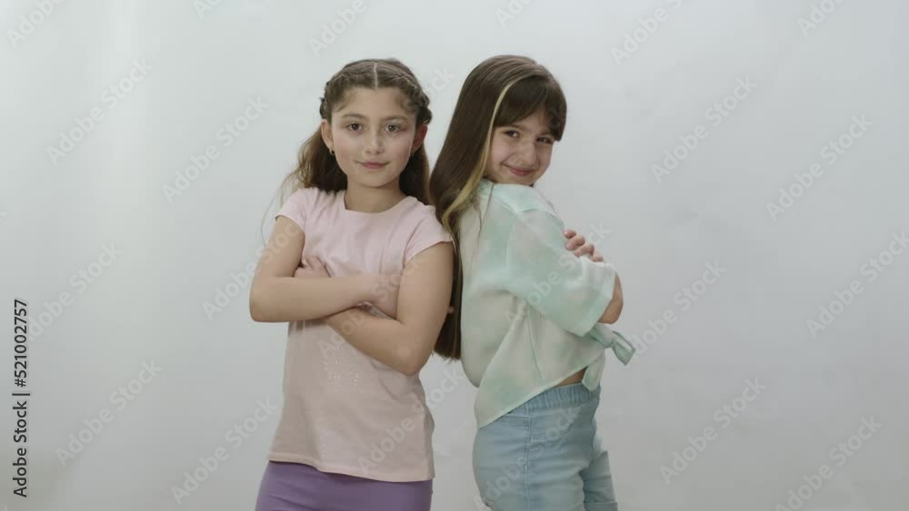 Two girls lean against each other in isolation. Energetic little girls ...