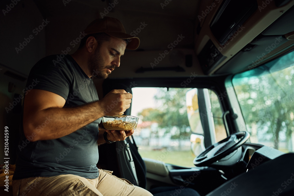 Young driver having lunch break in truck cabin. Stock-Foto | Adobe Stock