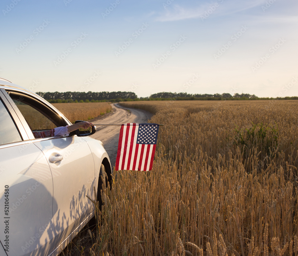 American flag hanging out of a car window in front of a ripe wheat ...