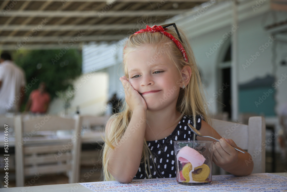 Happy little girl eating tasty fresh ice cream in cafe. Adorable little ...