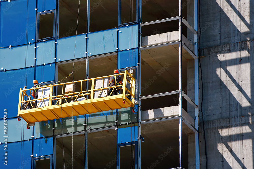 Workers team glazing facade of new building, men work at height in ...