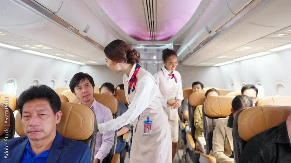 Asian woman flight attendant walking on airplane aisle closing luggage ...