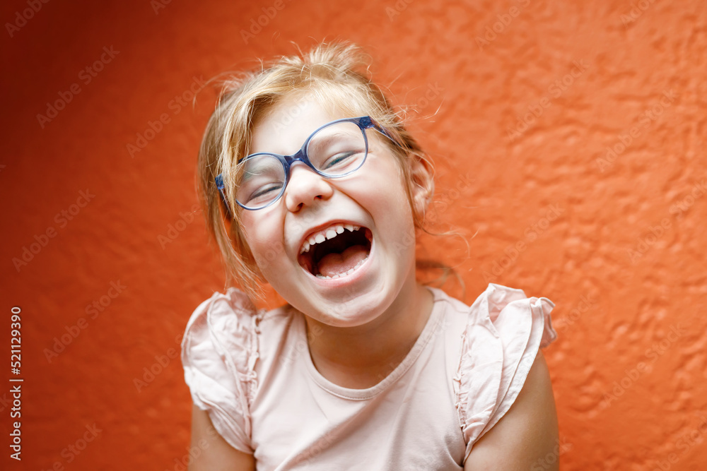 Happy little girl in glasses on orange background. Lauging and smiling ...
