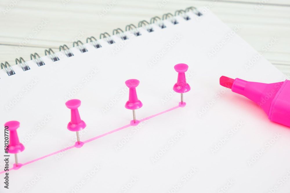 Marker-drawn line with milestone dots and paper pins on a white notepad ...
