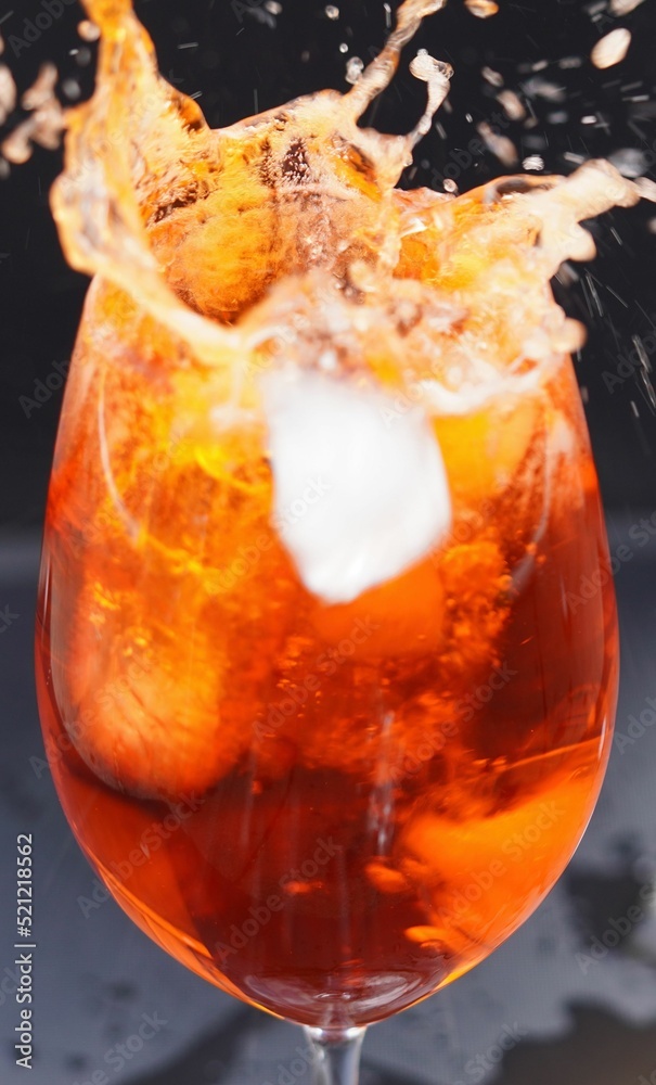 Vertical closeup of a glass filled with splashing Spritz Veneziano, an ...