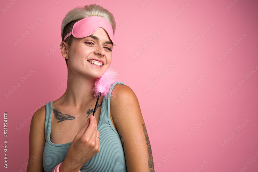 Sexy woman wearing sleep mask touching her face with erotic feather ...