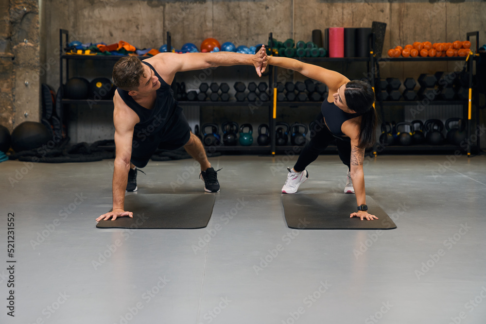 Happy sporty couple giving high five to each other while doing push up together in gym Stock ...