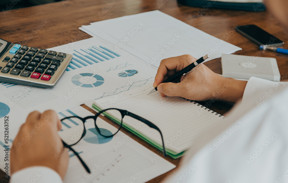 businessman using pen writing math report calculate graphs and ...