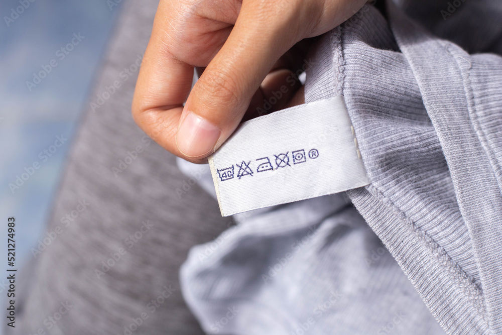 Women reading instructions on clothing labels, laundry care labels ...