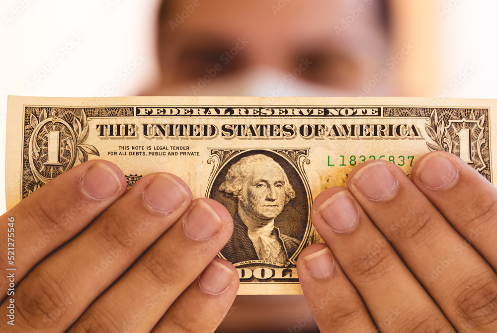 Um homem jovem segurando uma cédula de 1 dólar dos Estados Unidos ...