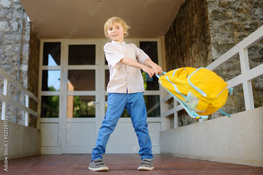 Little student boy with a backpack at the door of school building ...