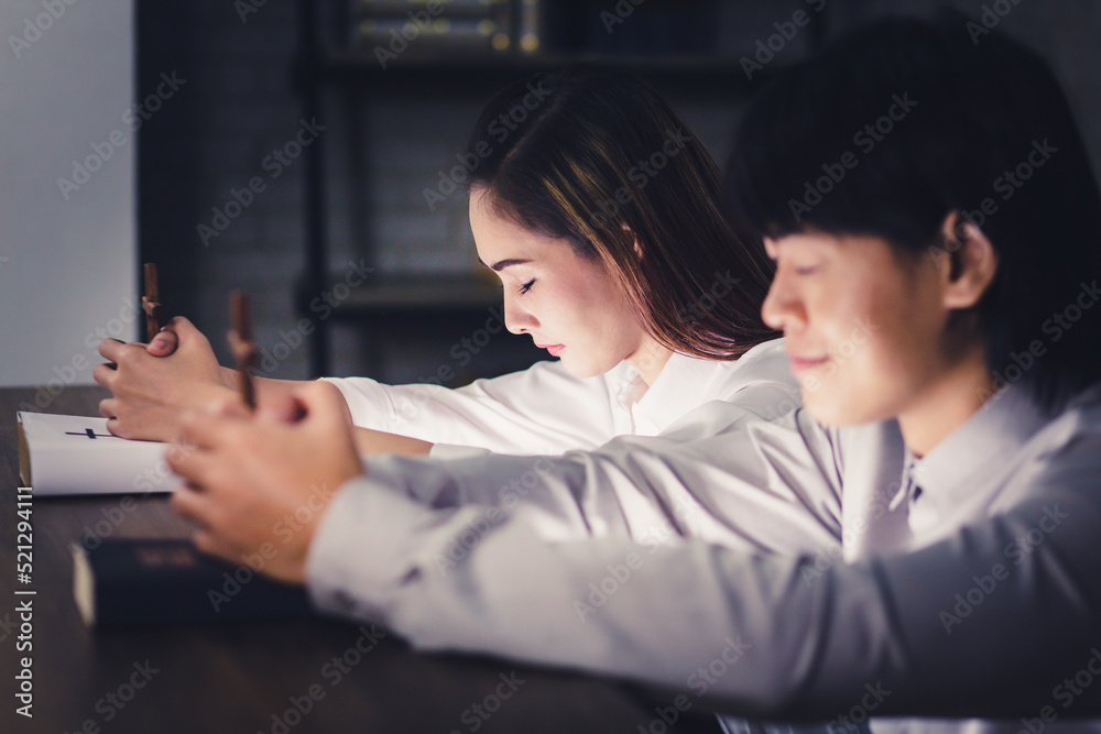 Christian Asian man and woman sitting at table and praying while ...