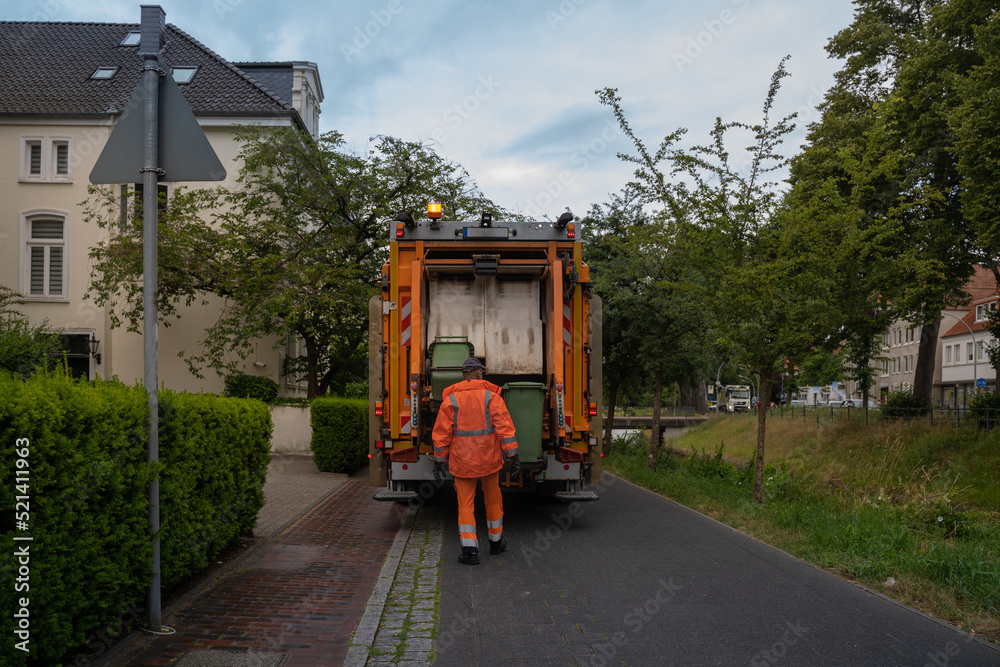 Garbage man loads garbage cans into a garbage truck Stock Photo | Adobe ...