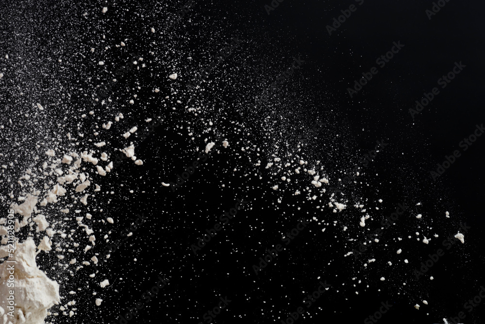 Flying white flour, powder on a black background. Spray of particles ...