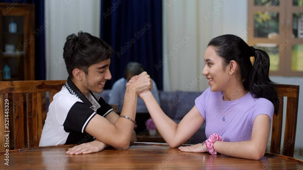 A teenage girl and her brother doing arm-wrestling - physical strength ...