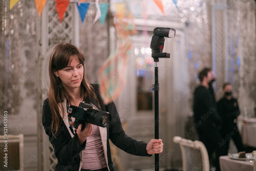 Girl photographer with a camera at work on the set in the banquet hall ...