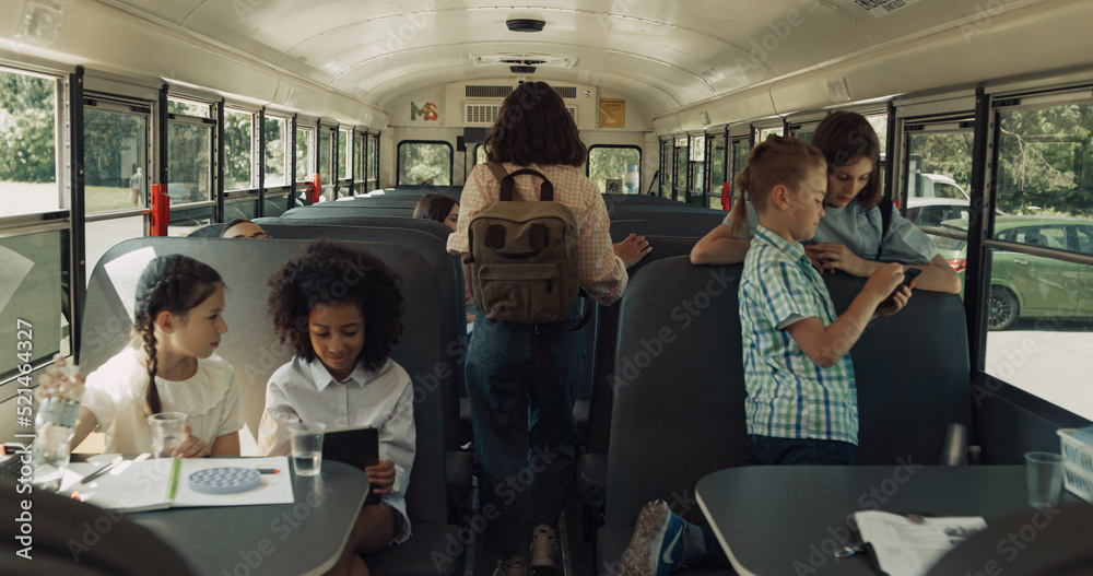 Teenage pupils boarding school bus. Diverse children using gadgets in ...