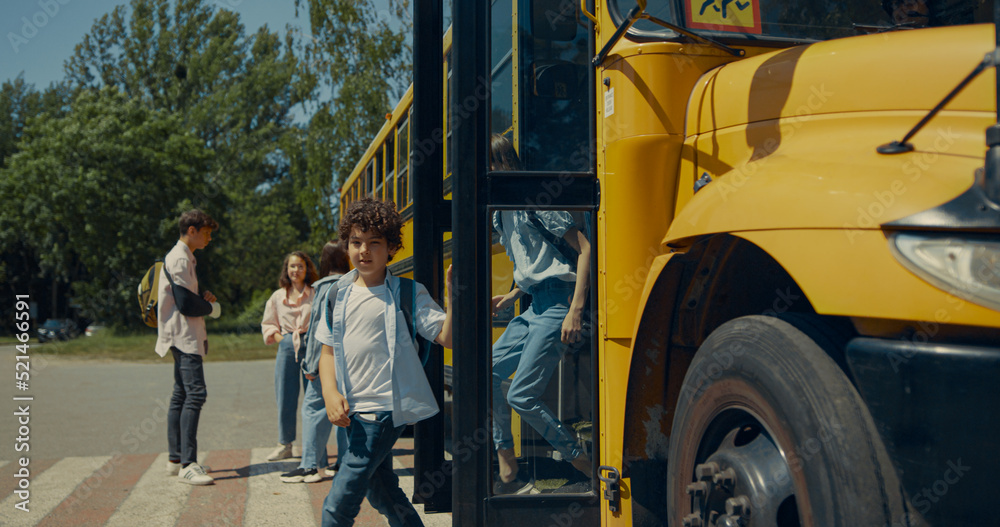 Two school children going out schoolbus. Teenagers standing at bus ...