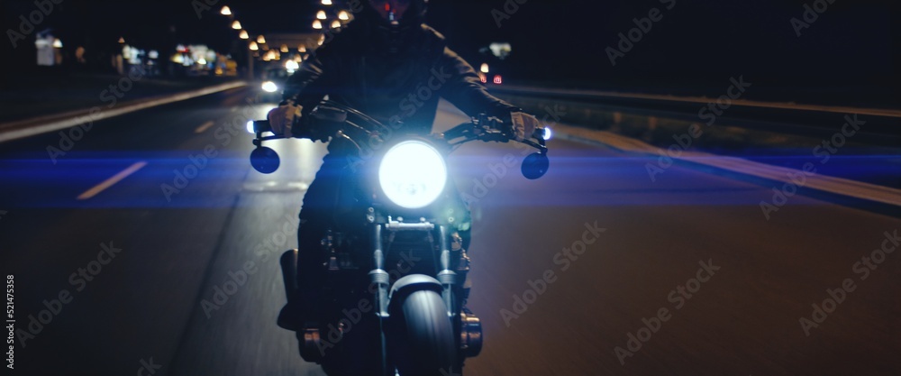 Biker riding his custom built cafe racer motorcycle through city at ...