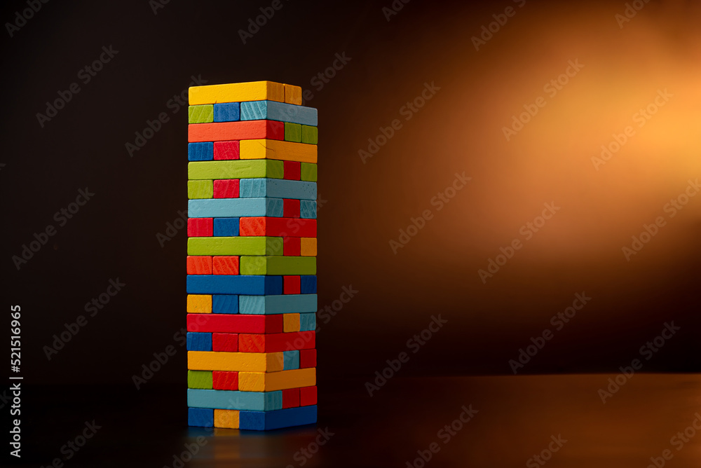 Board game Jenga Tower made of wooden blocks. A tower of unevenly ...