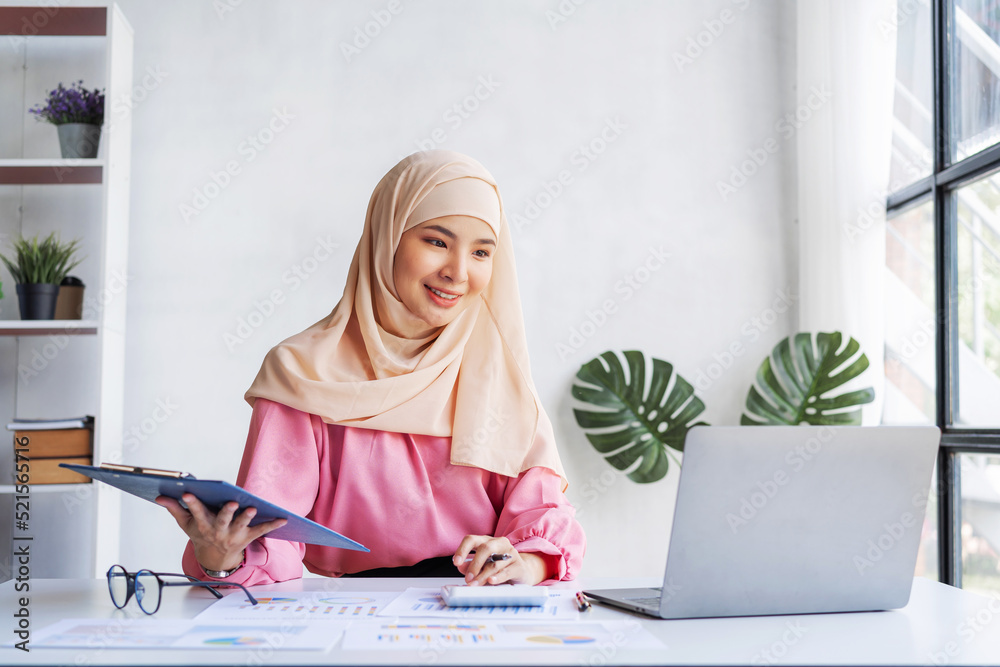 Young Asian pretty muslim lady in hijab working with laptop in office ...