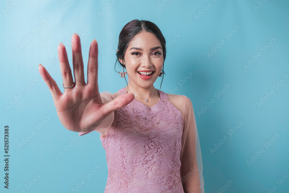 Young Asian woman wearing modern kebaya over blue isolated background ...