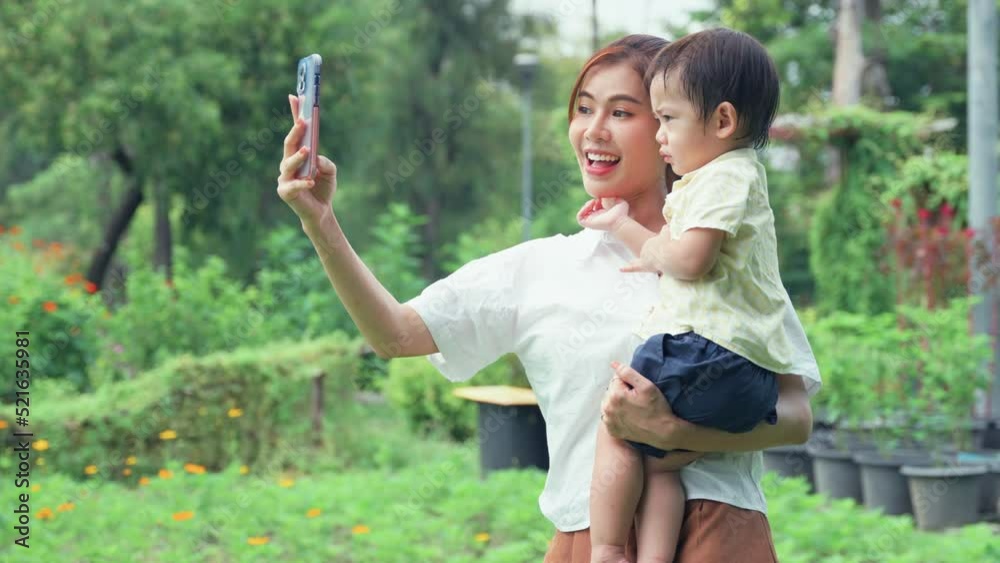 Asian Young Mother Teasing Her Son Using A Mobile Phone To Open Something That His Son Likes To