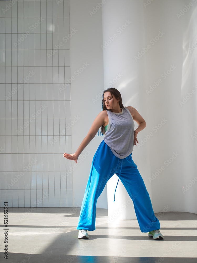 Modern dance, stylish young brunette in baggy blue pants dancing in ...