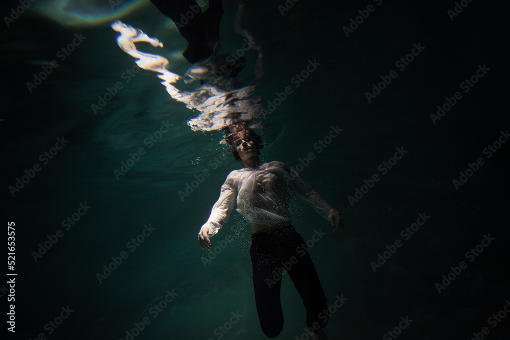 Beautiful underwater shooting, guy in white shirt and pants has fallen ...