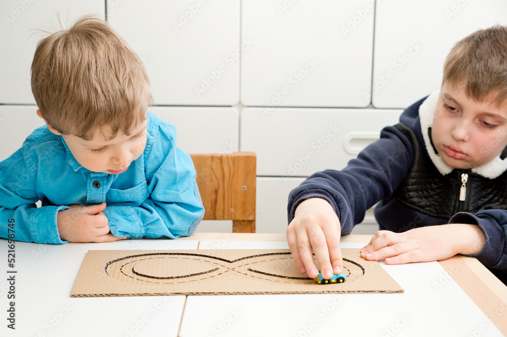Paper race track. Two brothers follow the lines with a car. Implement ...