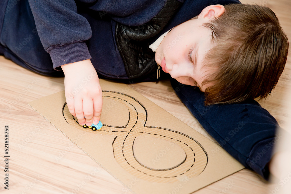 Corrugated carton race track. Boy with autism follow the lines ...