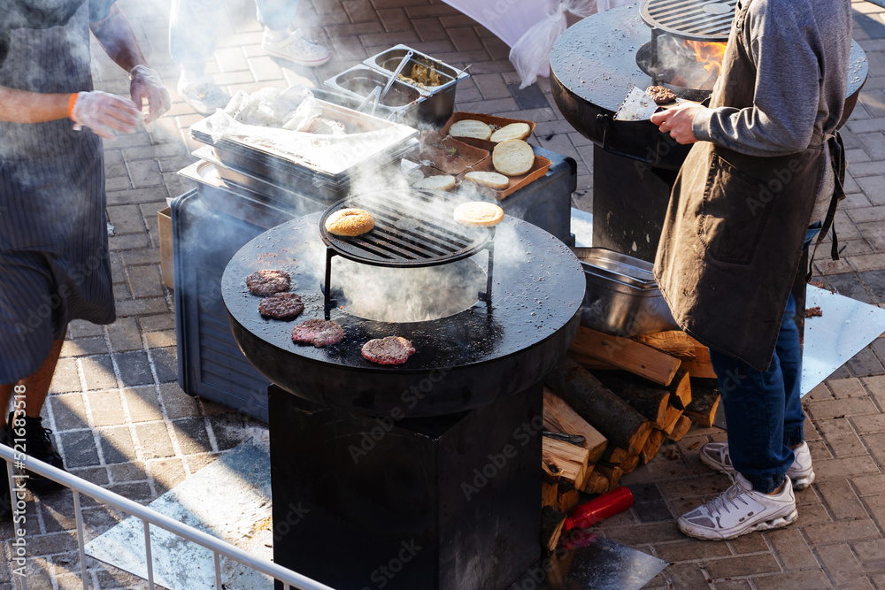 Cooking hamburgers on the grill. A large brazier with buns and cutlets ...