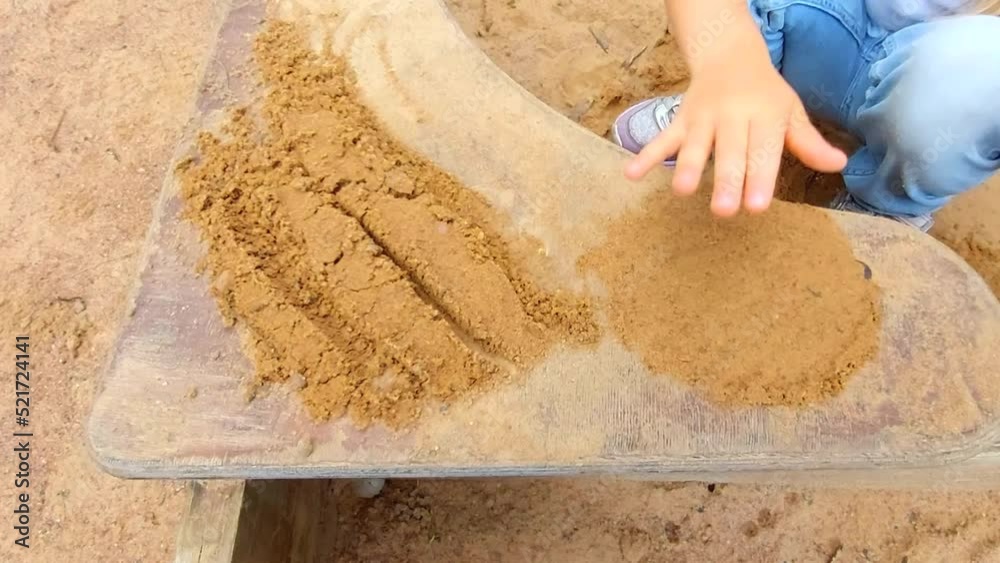 Little girl playing in sand box outdoor. Close up of child hand playing ...