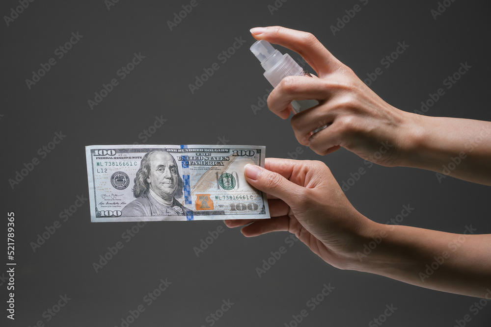 Lady hand applying alcohol spray hand sanitizer towards the 100 US ...
